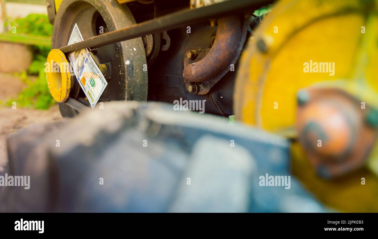 A hundred dollar bill lies on the engine of a small rural walk-behind ...