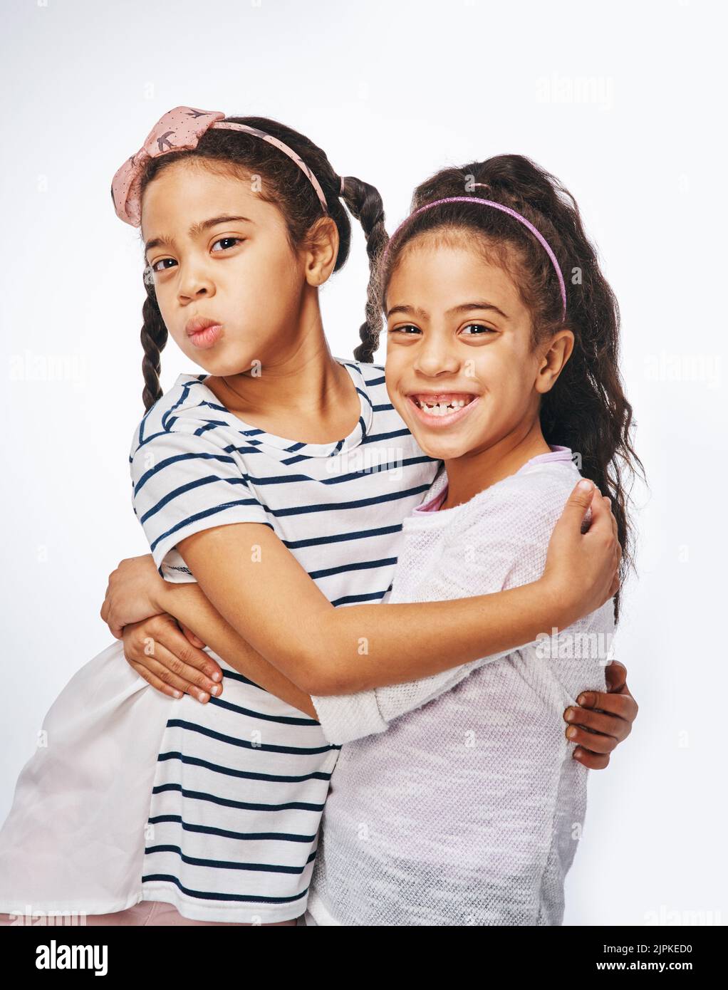 We are inseparable. two young girls embracing each other against a ...