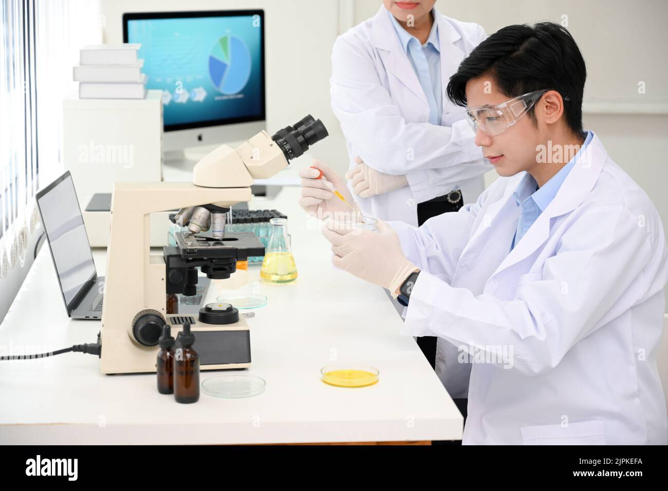 A professional young Asian male scientist is adjust specimen on a Petri ...