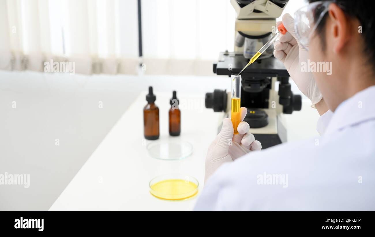 Talented young Asian male scientist concentrating adjusts a chemical ...