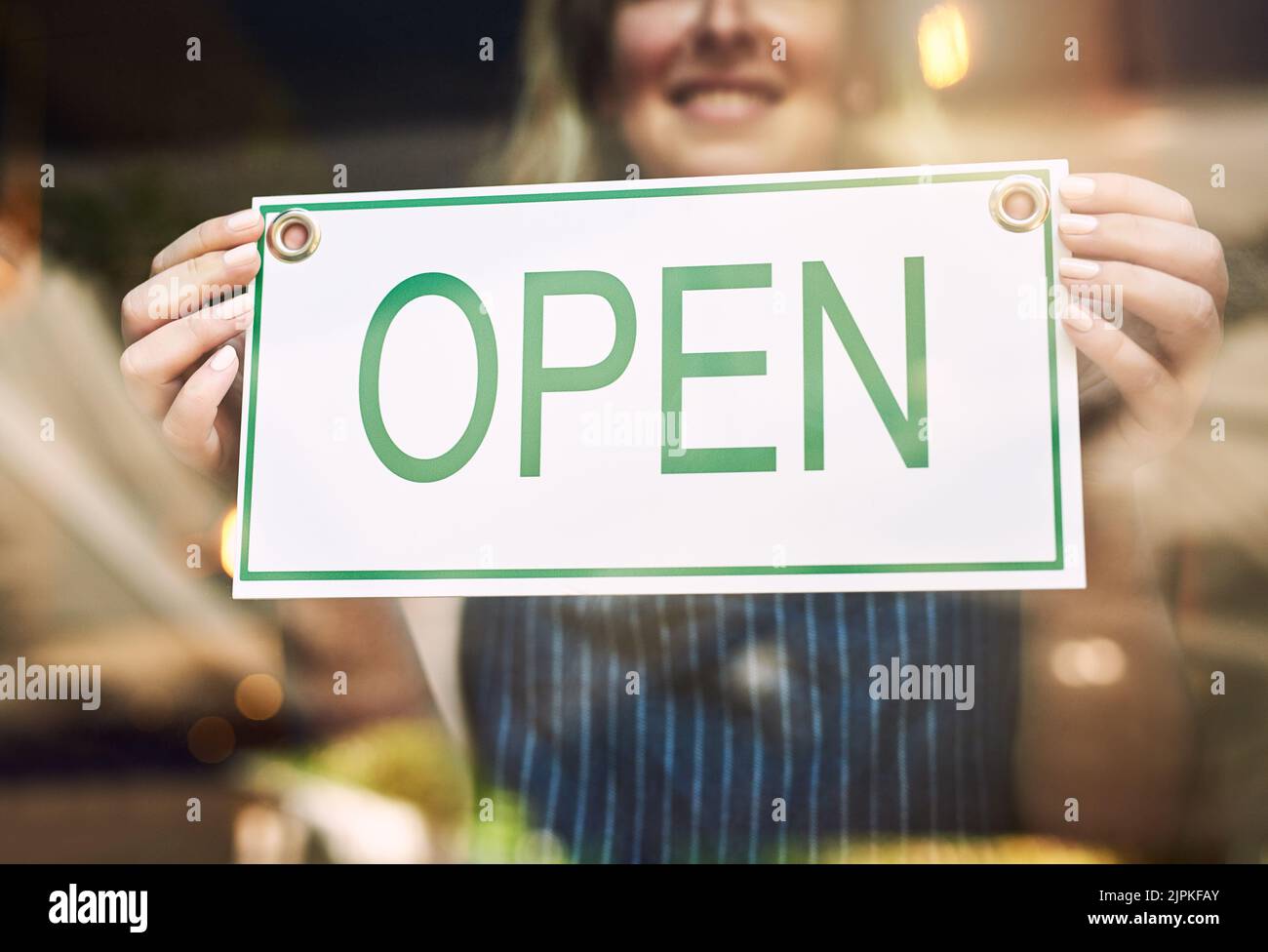 Were open, come inside. a woman putting up a open sign in a bar Stock ...