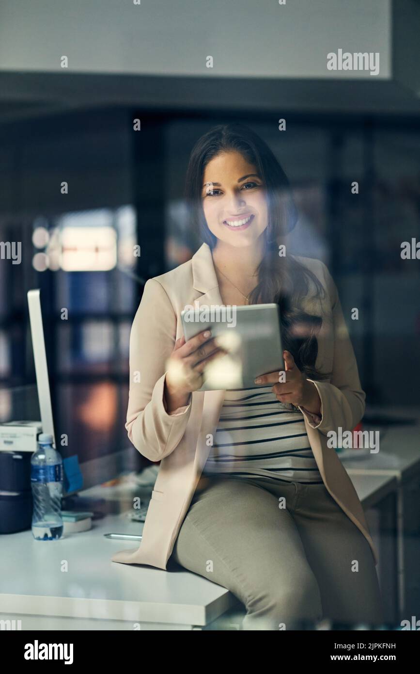 Ready for the late shift. a young businesswoman using a digital tablet ...