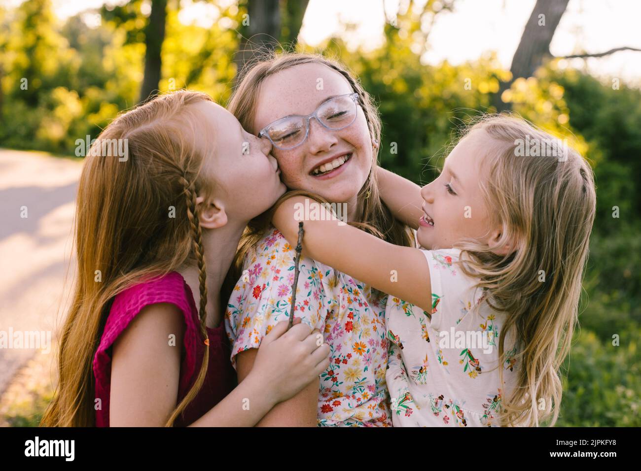 Young sisters laugh, hug and kiss in golden light Stock Photo - Alamy