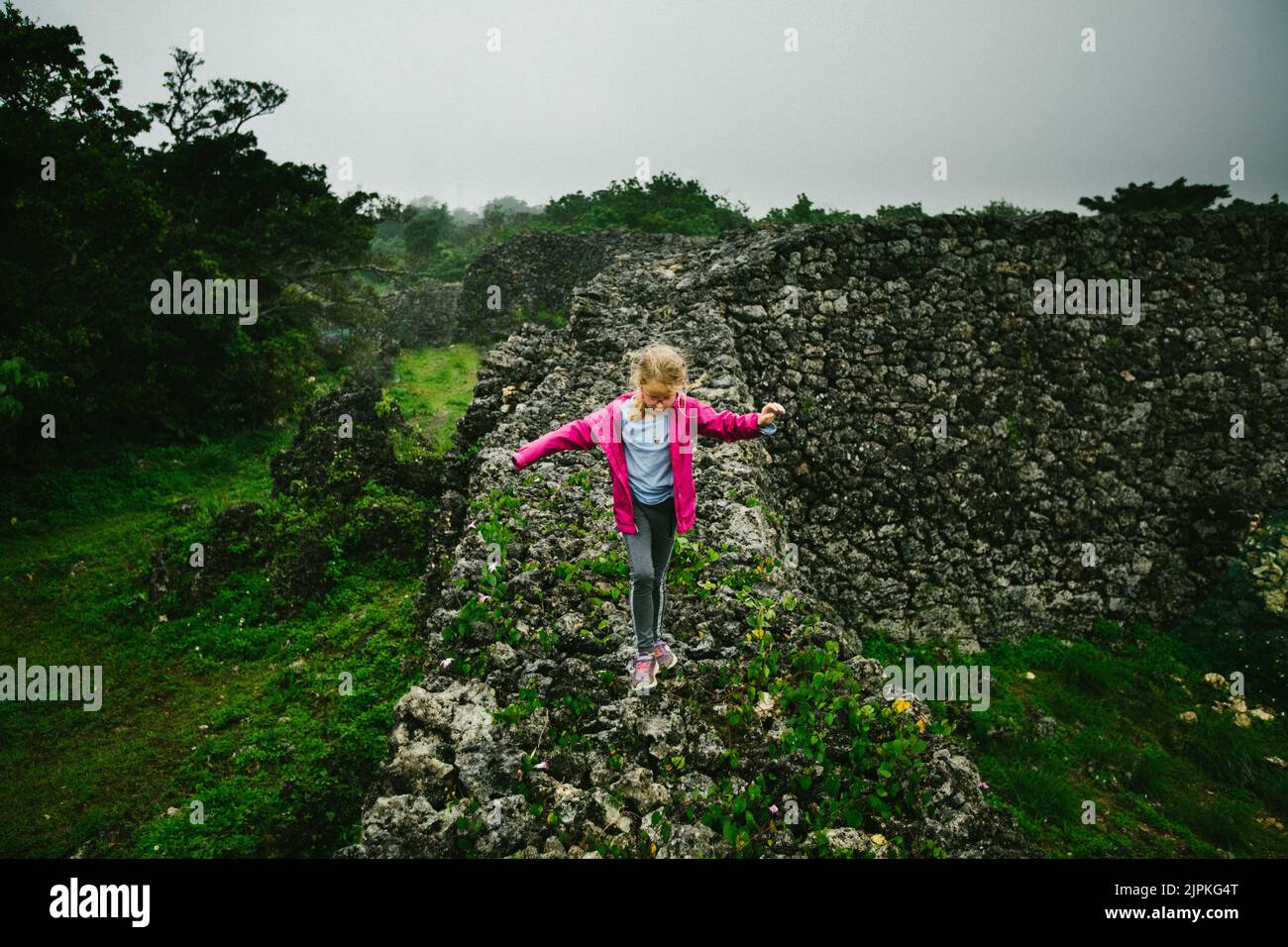 Girl child walks along castle ruin wall in tropical forest Stock Photo ...