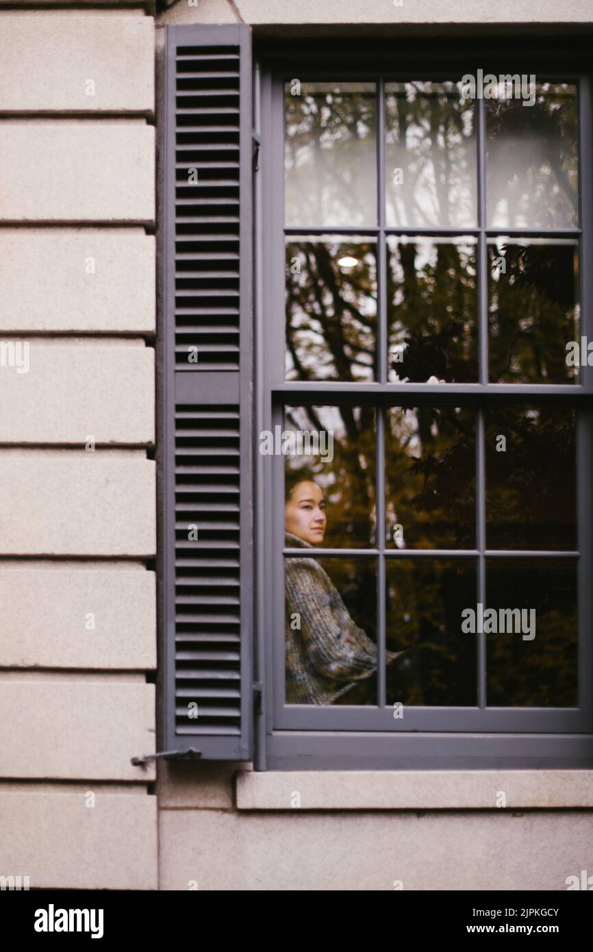 Young asian woman looks out window of home in fall season Stock Photo ...