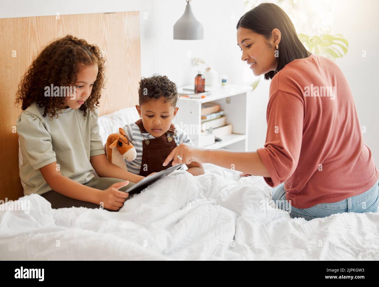 Mother and children browsing a digital tablet in the bed at home ...