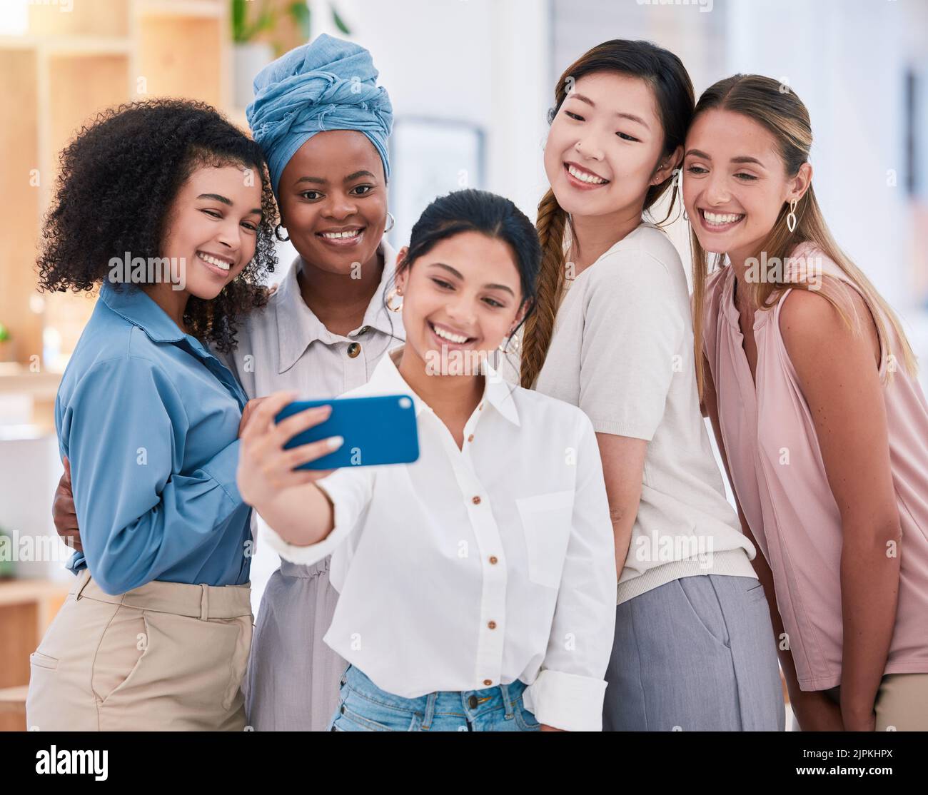 Diverse fun business friends taking selfies on a phone together in an ...
