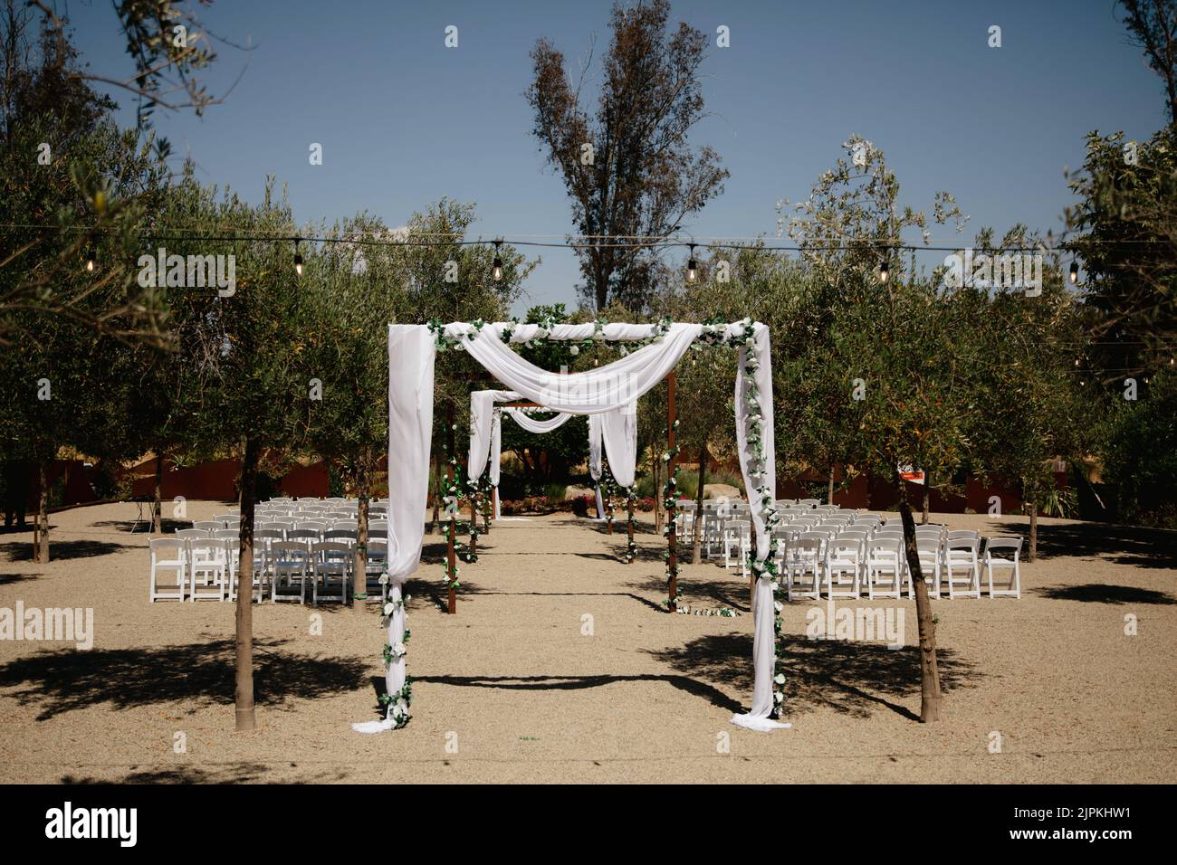 Square wooden wedding arches with white fabric draping and floral ...