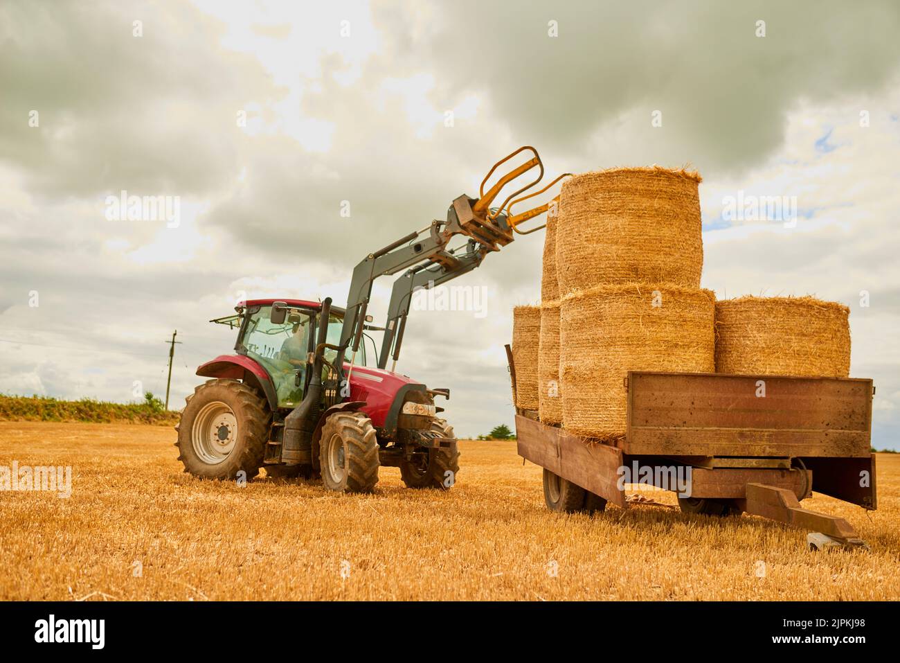 Keeping his farm neat and tidy. a farmer stacking hale bales with a ...