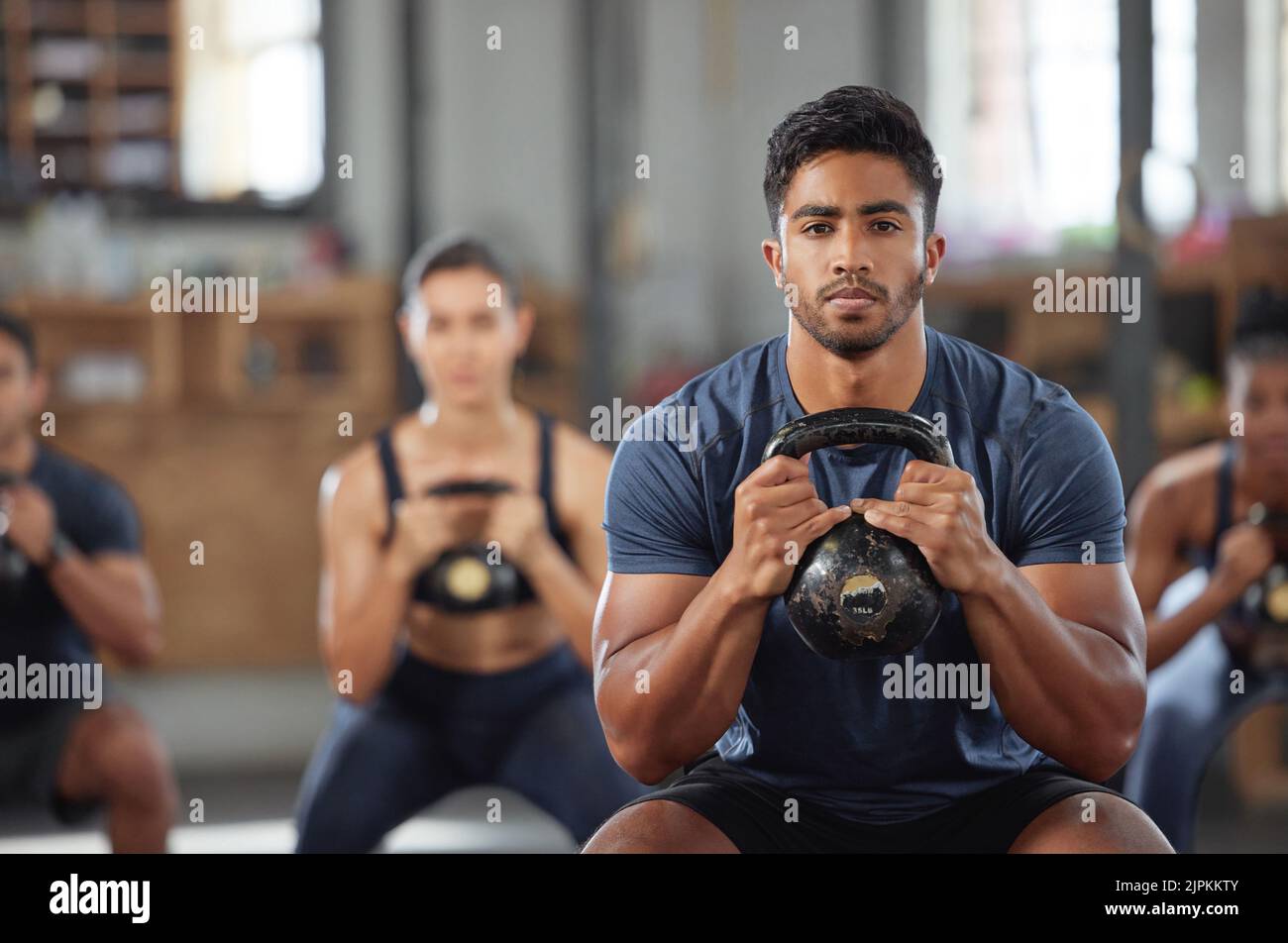 Personal trainer squatting with a team of athletes in a workout session ...