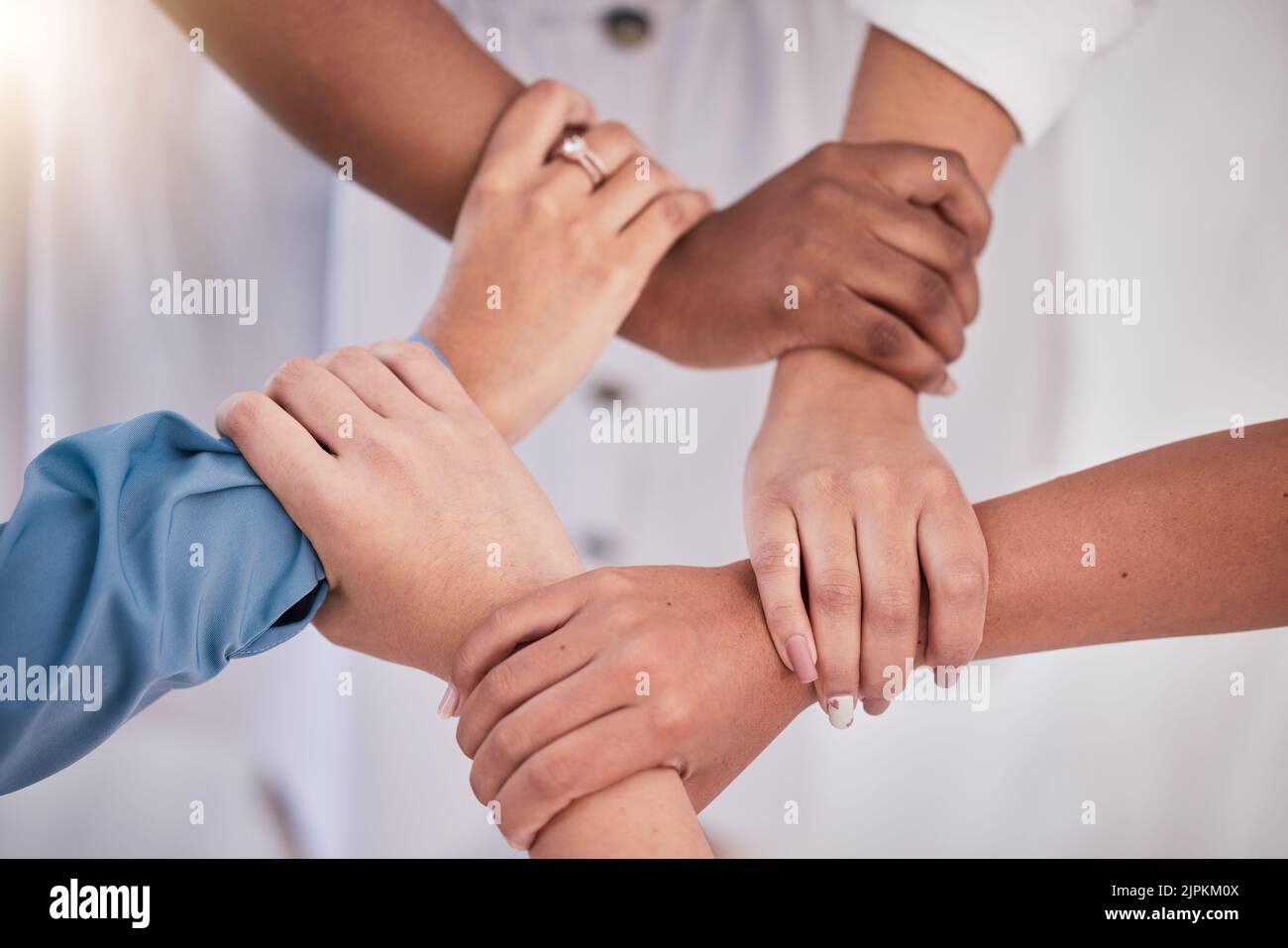 Diverse colleagues hands holding wrists from above in support of unity ...