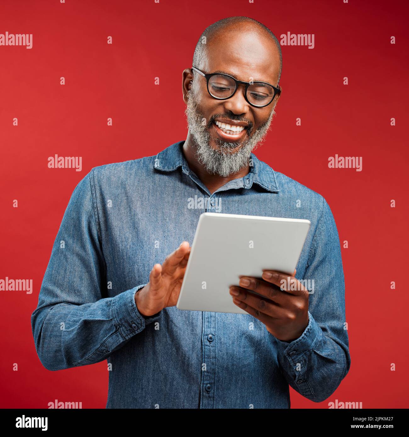 Smiling man browsing on a tablet online, networking on the internet and ...