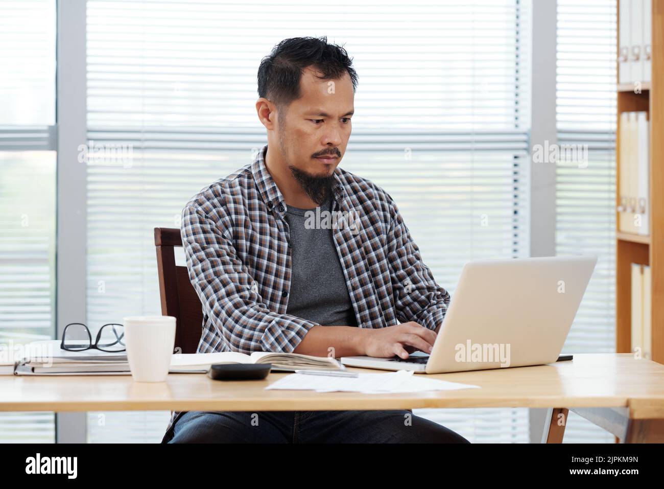 Filipino entrepreneur working on laptop in his office Stock Photo - Alamy