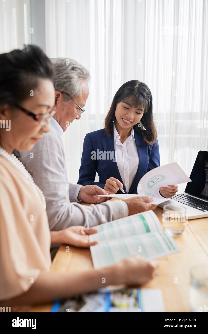 Pretty female manager explaining insurance policy terms to senior ...