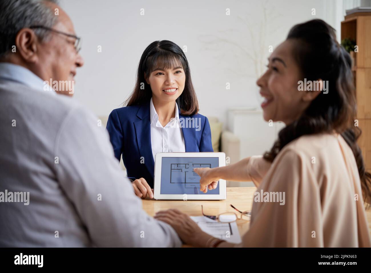 Pretty young real estate broker showing apartment plan to her senior clients Stock Photo - Alamy