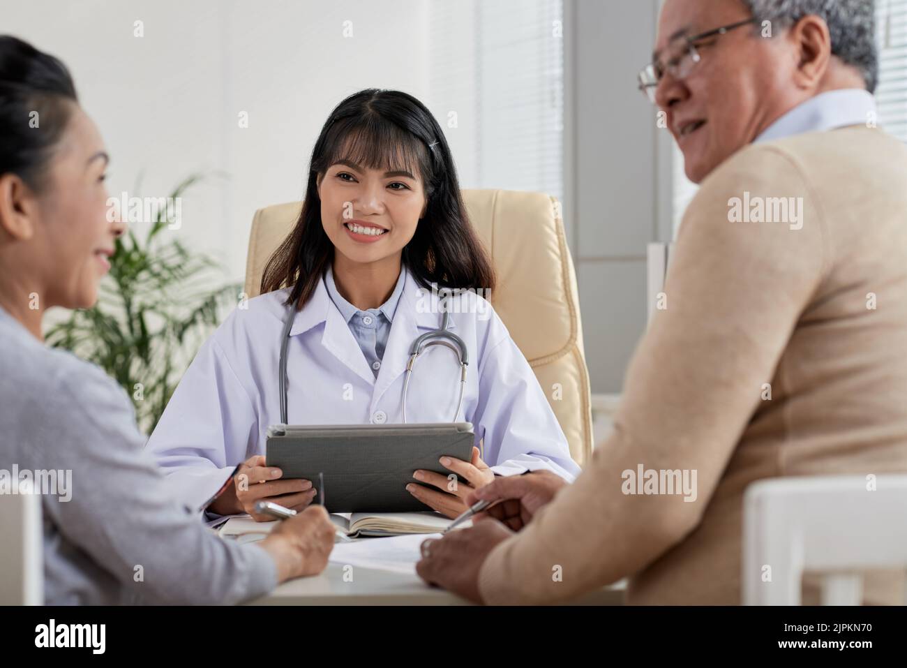 Young Vietnamese female doctor talking to senior patients Stock Photo ...
