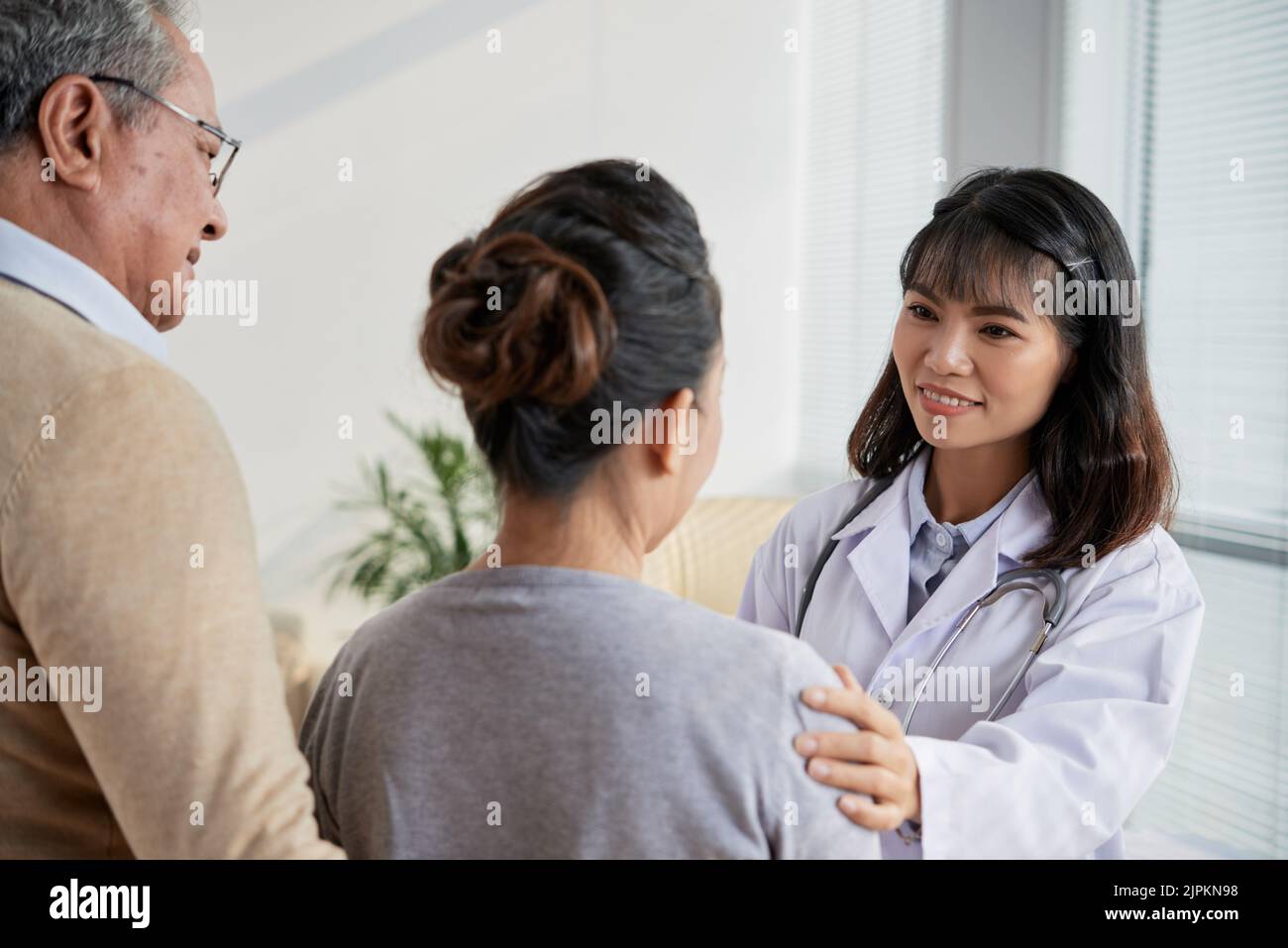 Female Vietnamese doctor talking to senior couple Stock Photo - Alamy