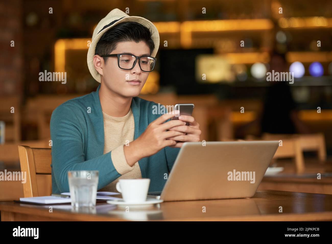 Handsome young Asian man reading messages in his smartphone Stock Photo ...