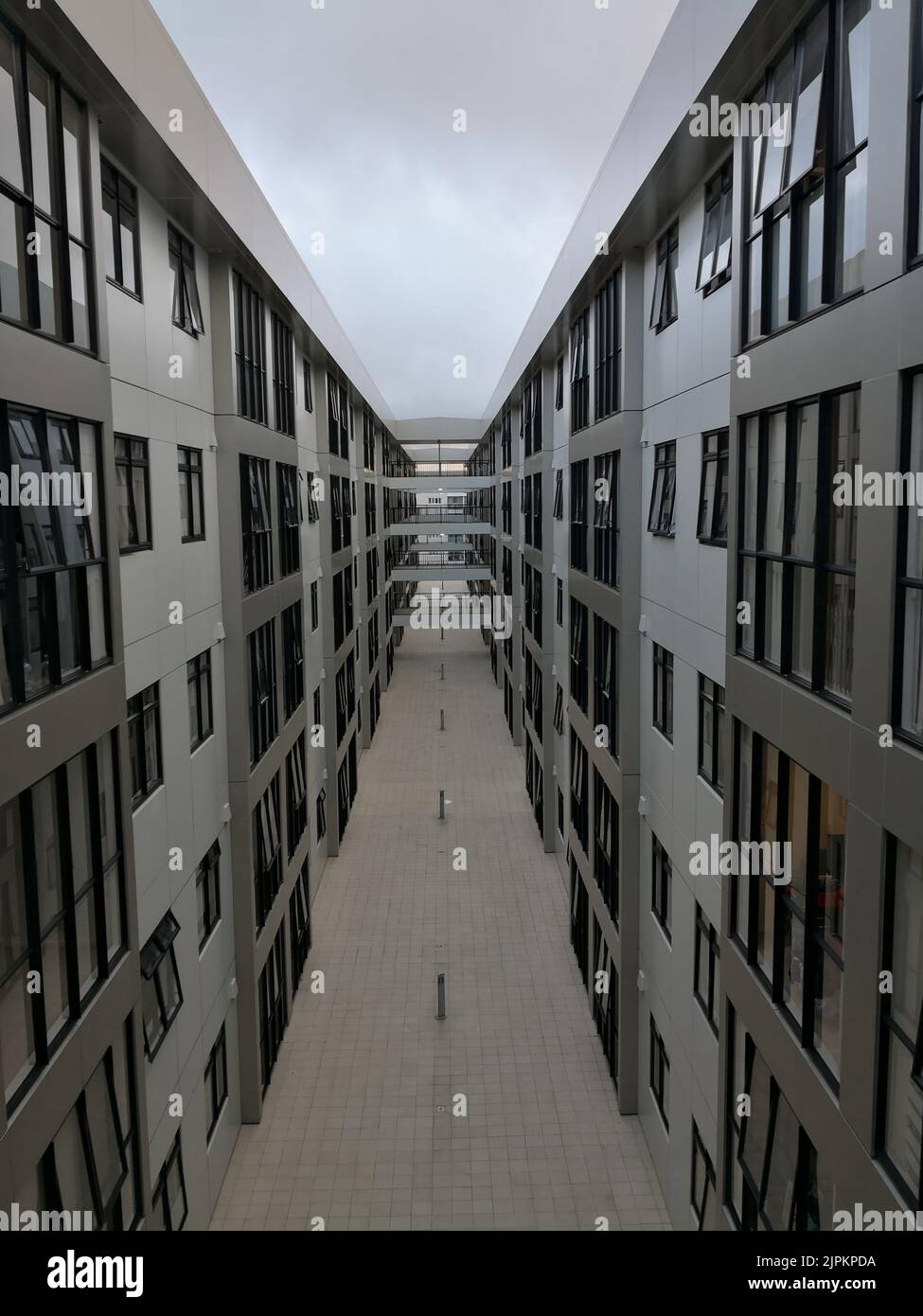 An outside corridor between gray modern buildings Stock Photo - Alamy