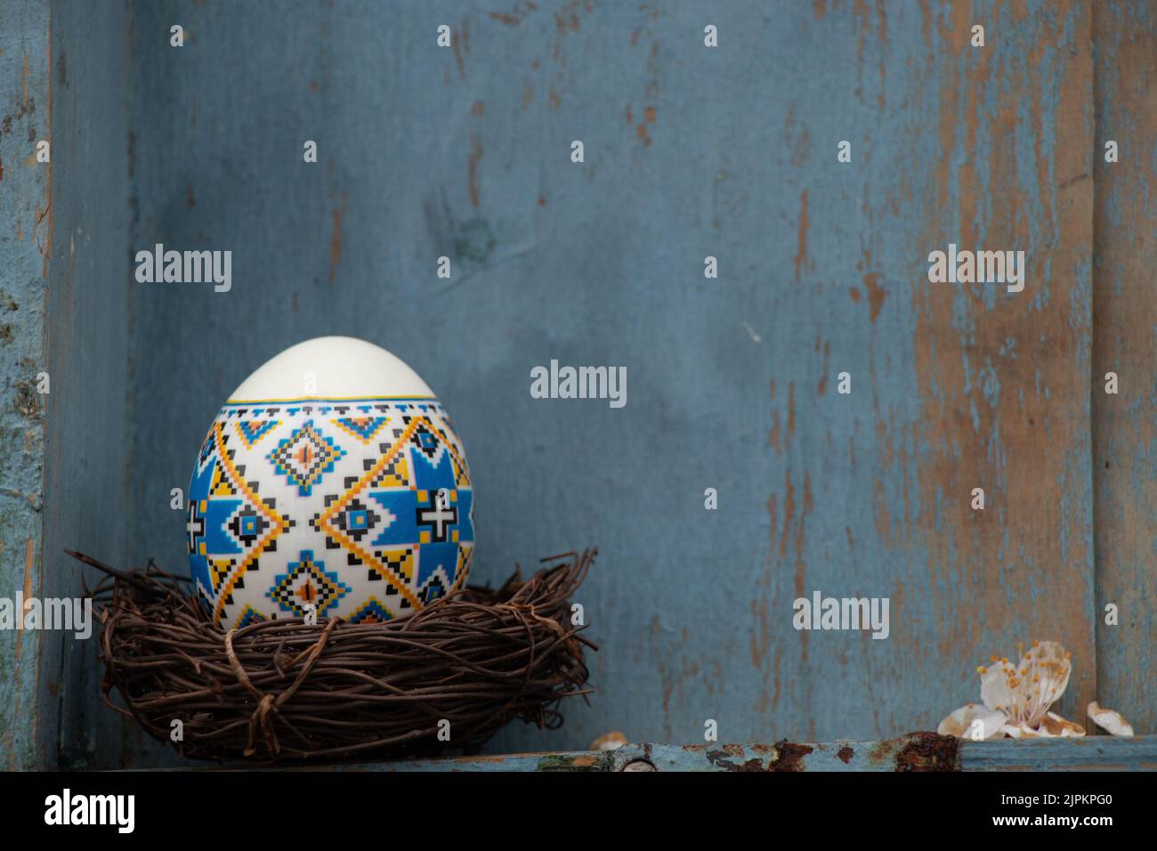 Painted chicken egg in a straw basket on a wooden background in Ukraine ...