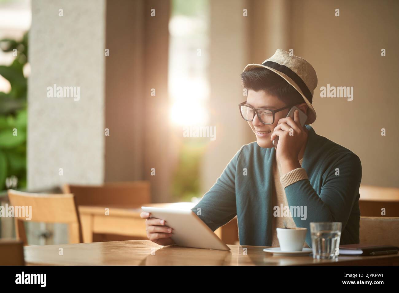 Young Vietnamese man calling on phone when reading data in digital ...