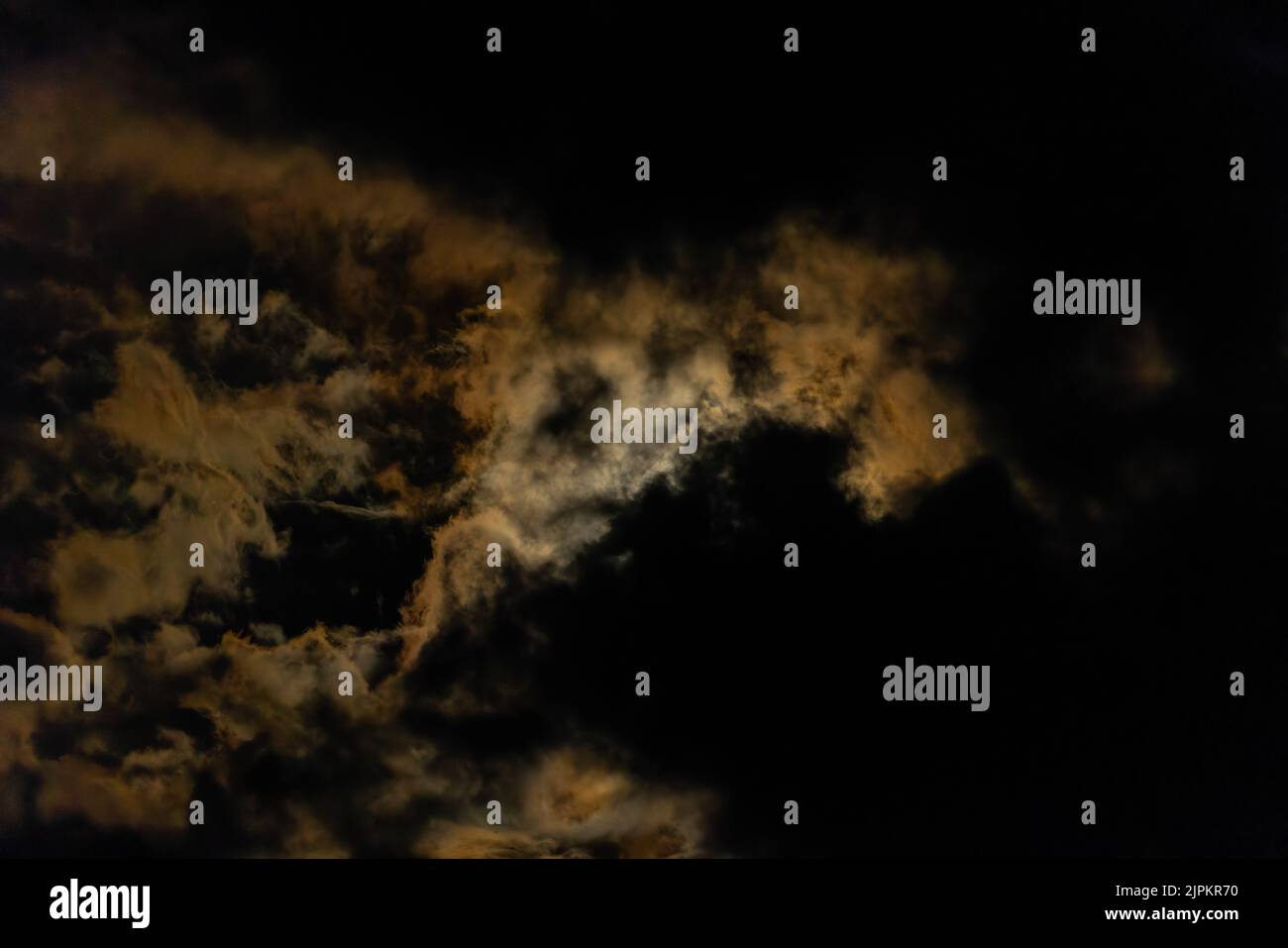 Dark black clouds lit by orange moonlight at night Stock Photo - Alamy