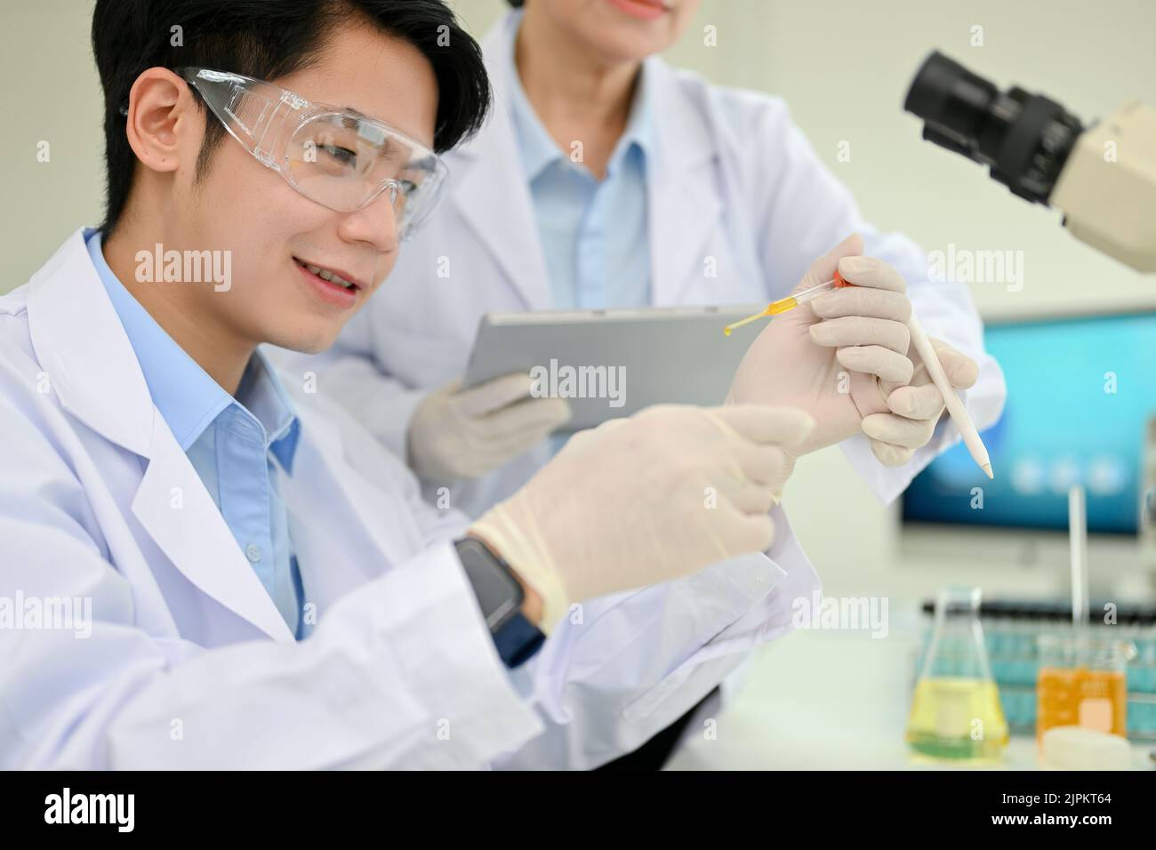 Smart millennial Asian male scientist adjusts a virus sample in a Petri ...
