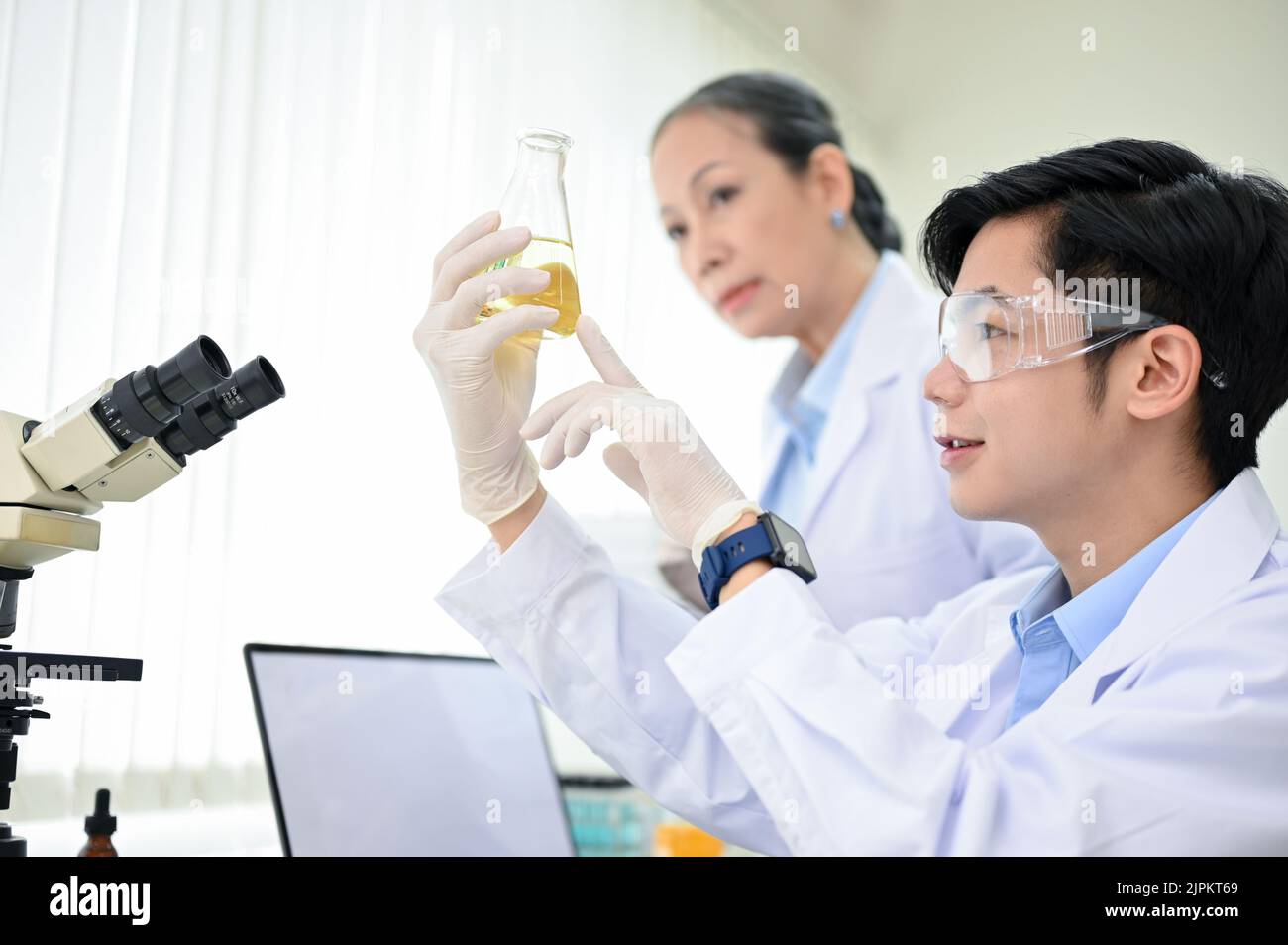 Smart and handsome young Asian scientist working in the lab with his ...