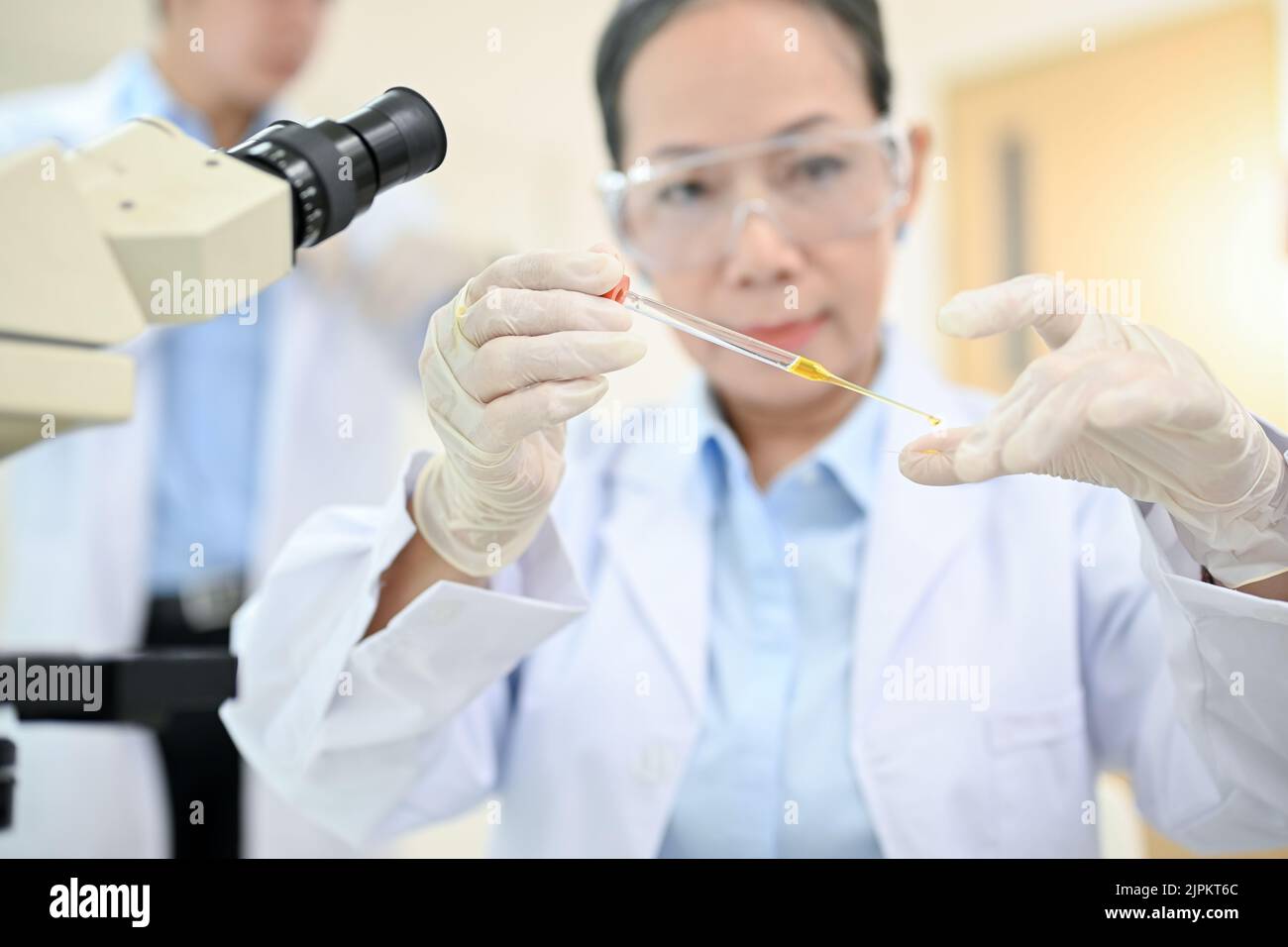 Professional Asian senior female scientist or medical technician using ...