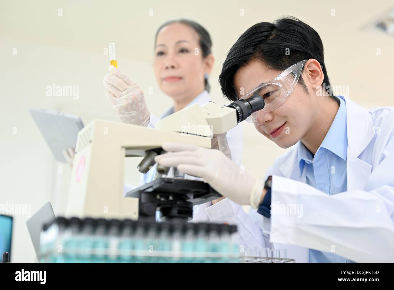 An expert young Asian male scientist or medical chemist examining a ...