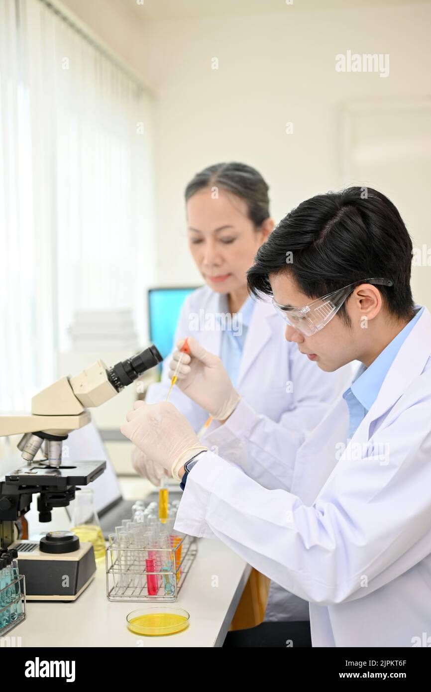 Concentrated young Asian male scientist or chemist working in the ...