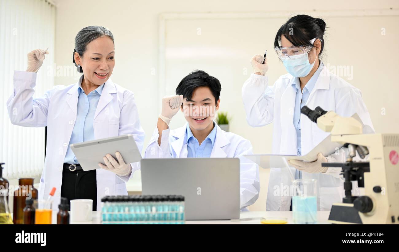 Happy and cheerful Asian scientist team working together in the laboratory succeeds with their ...