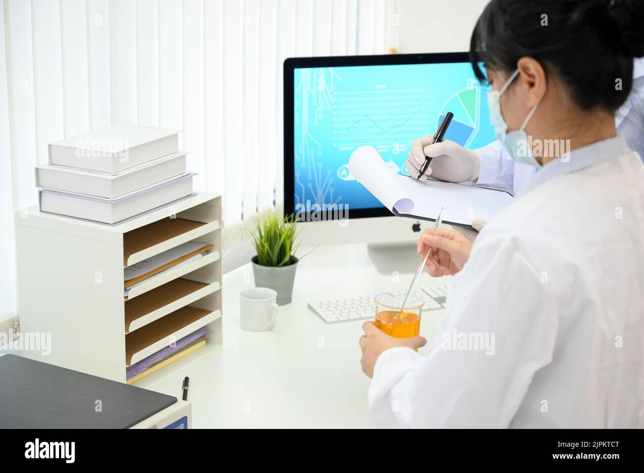 Concentrated young Asian female scientist or chemist working with her ...