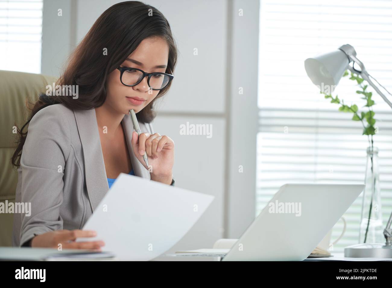 Pensive Asian business lady checking important document Stock Photo - Alamy