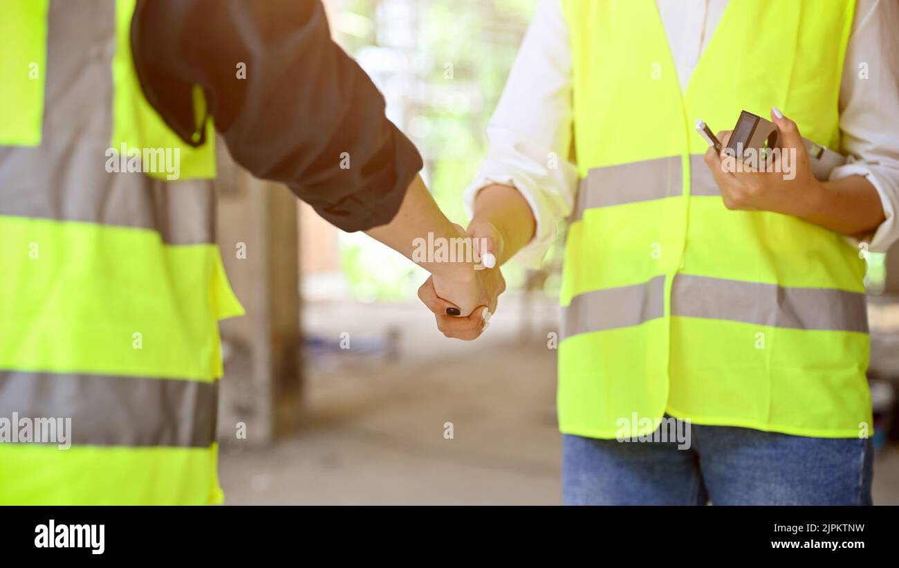 A professional male civil engineer in the safety uniform shaking hand ...
