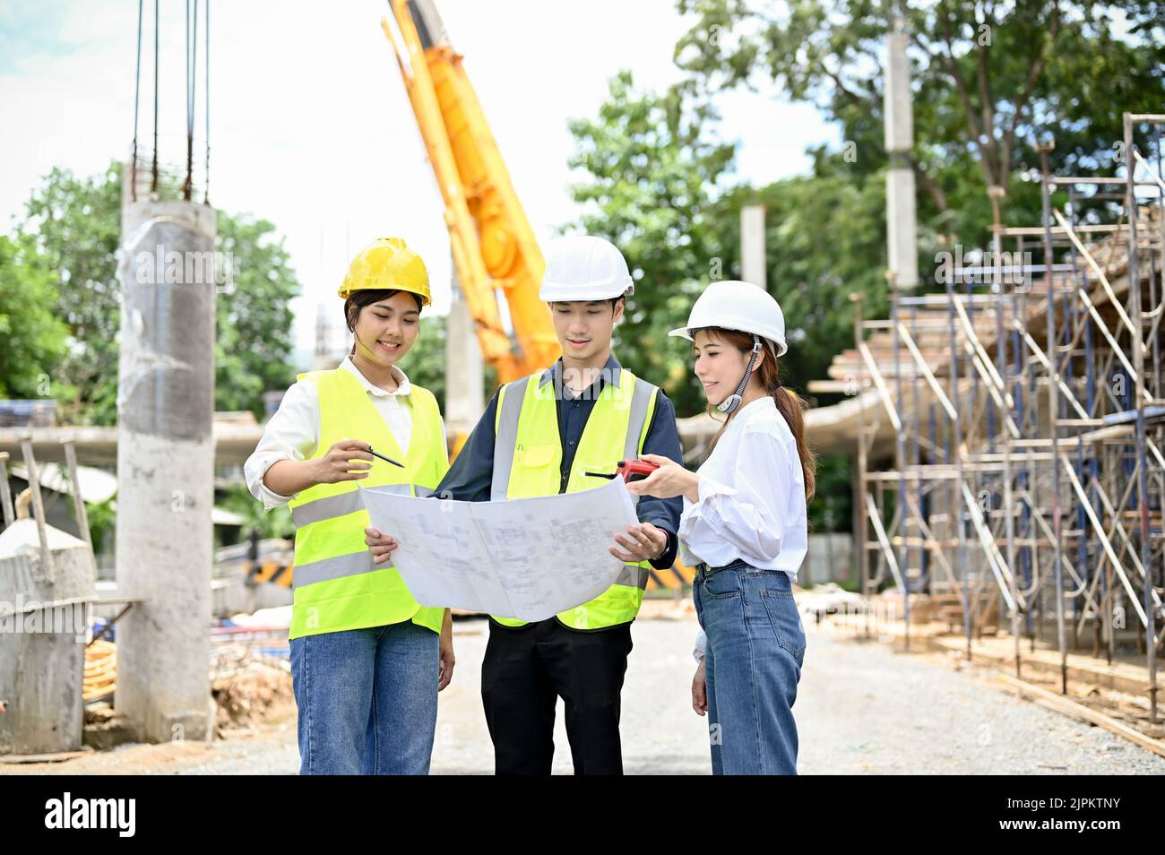 A team of talented Asian-young civil engineers looking at the blueprint ...