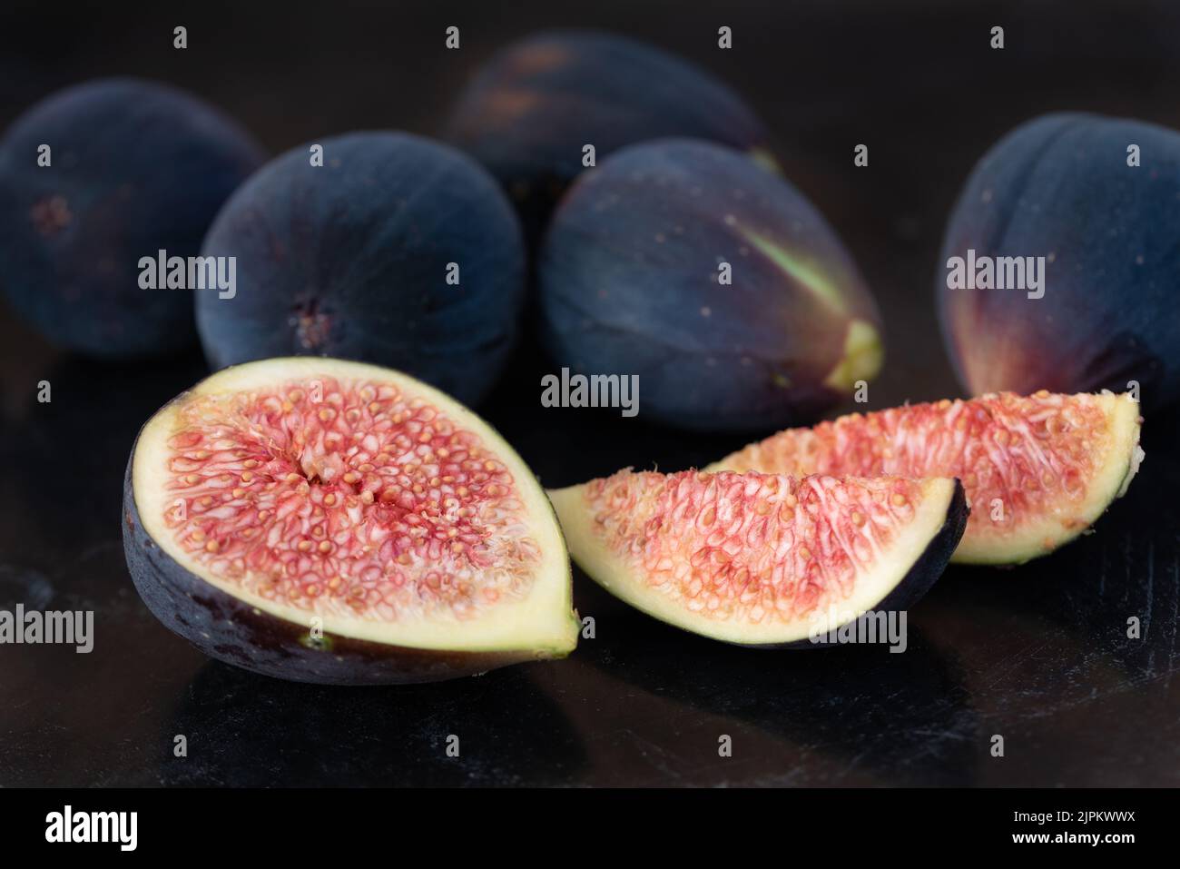 red sliced fresh figs lie next to each other against a dark background ...