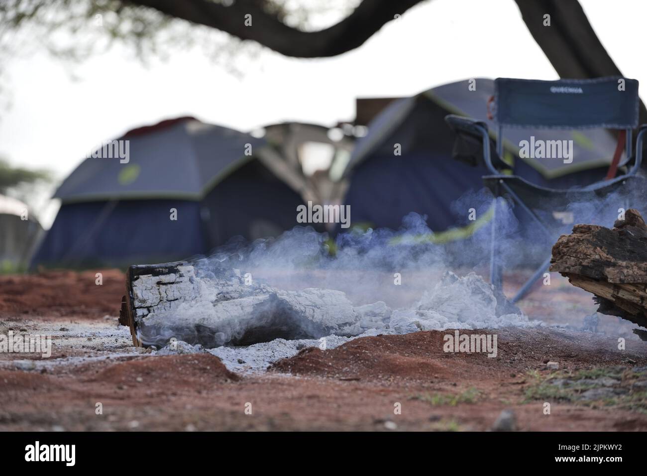 A burned log with smoke in camping setting Stock Photo - Alamy