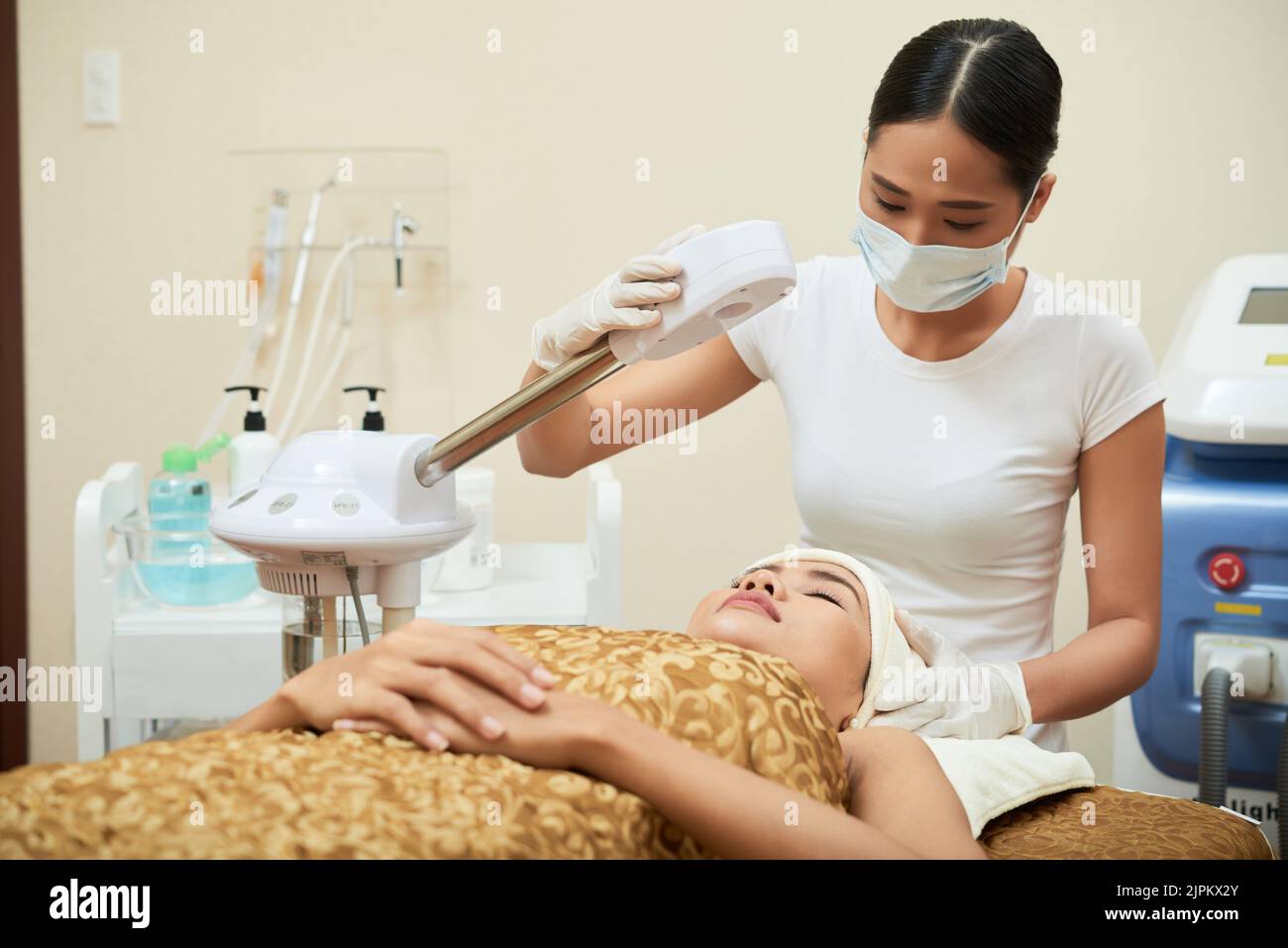Highly professional Vietnamese cosmetologist wearing rubber gloves and ...