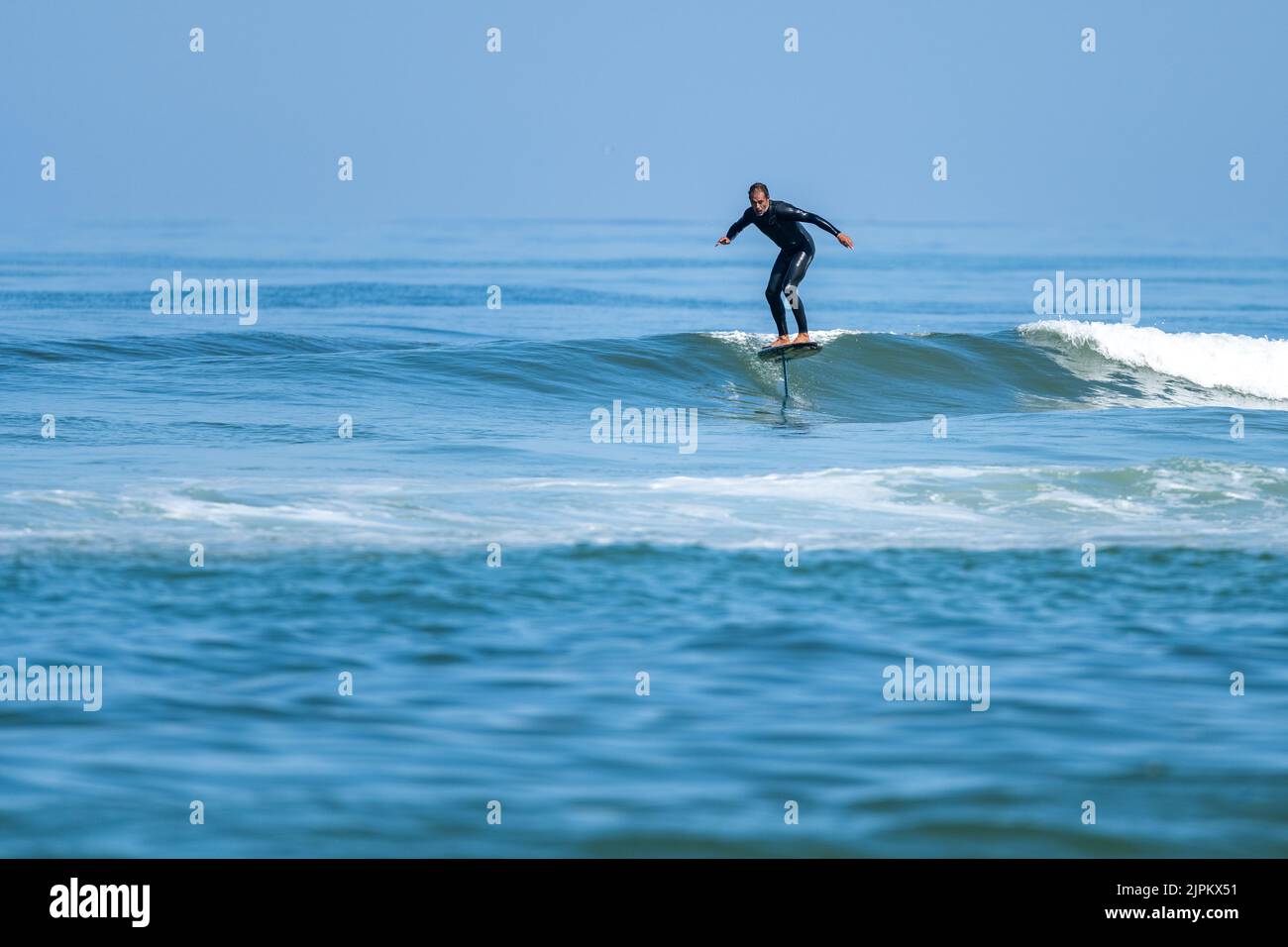 A middle aged man doing some foil surfing or hydrofoil surfing in the ...