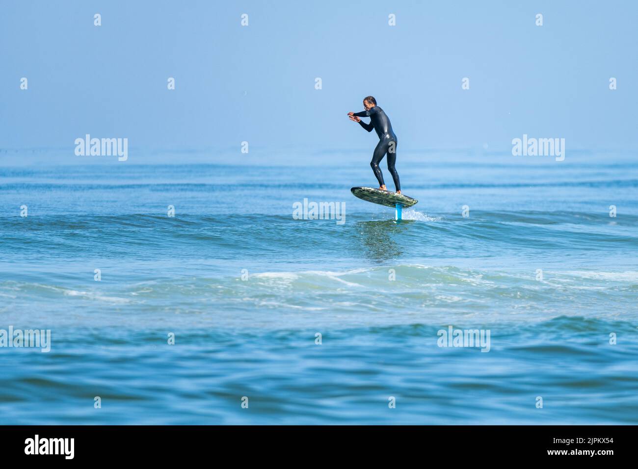 A middle aged man doing some foil surfing or hydrofoil surfing in the ...