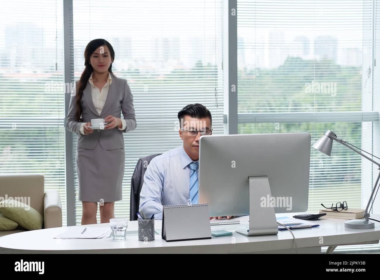 Assistant bringing coffee to her Vitenamese entrepreneur Stock Photo ...