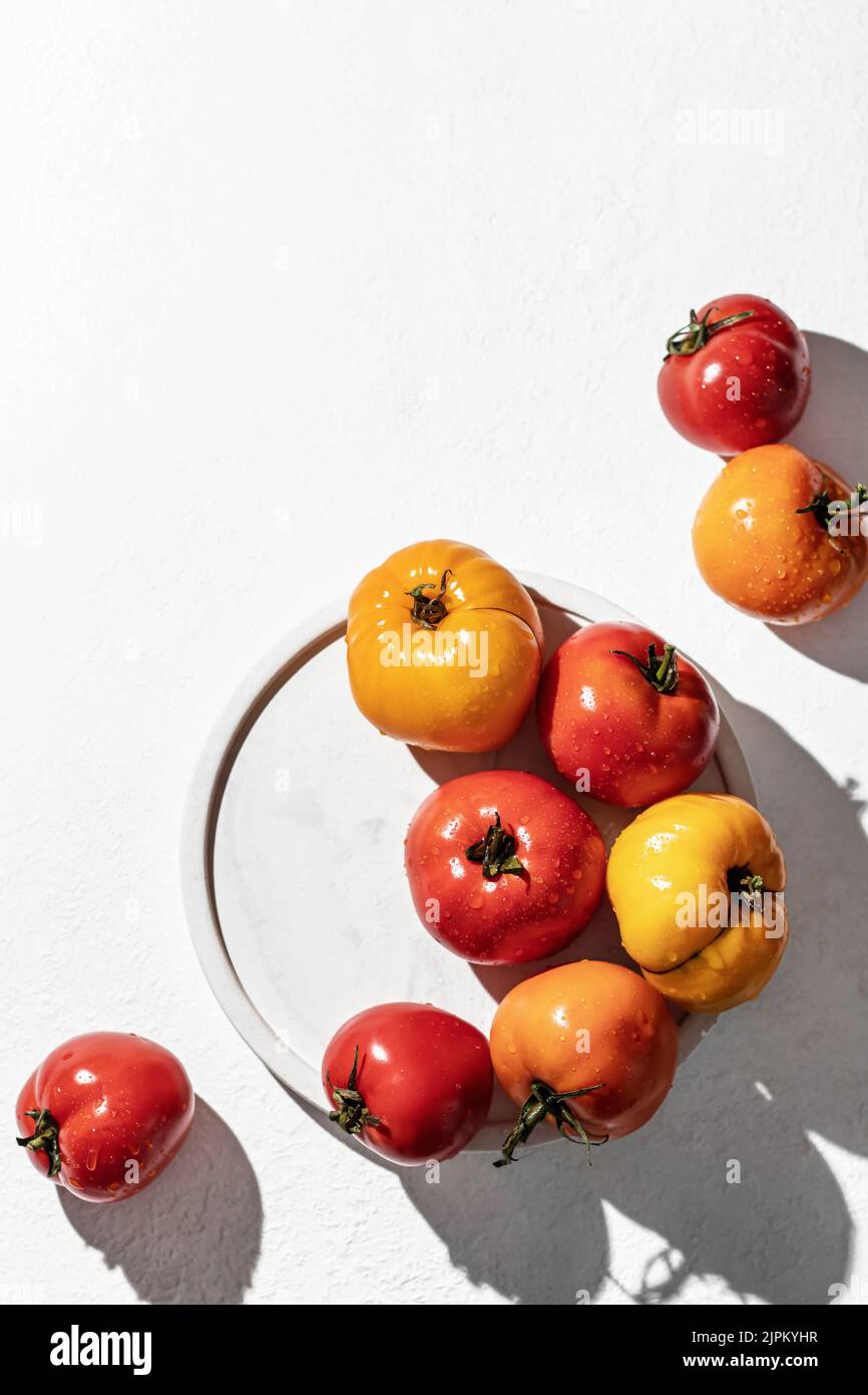 Fresh colorful tomatoes with water drops on the surface on plate with ...