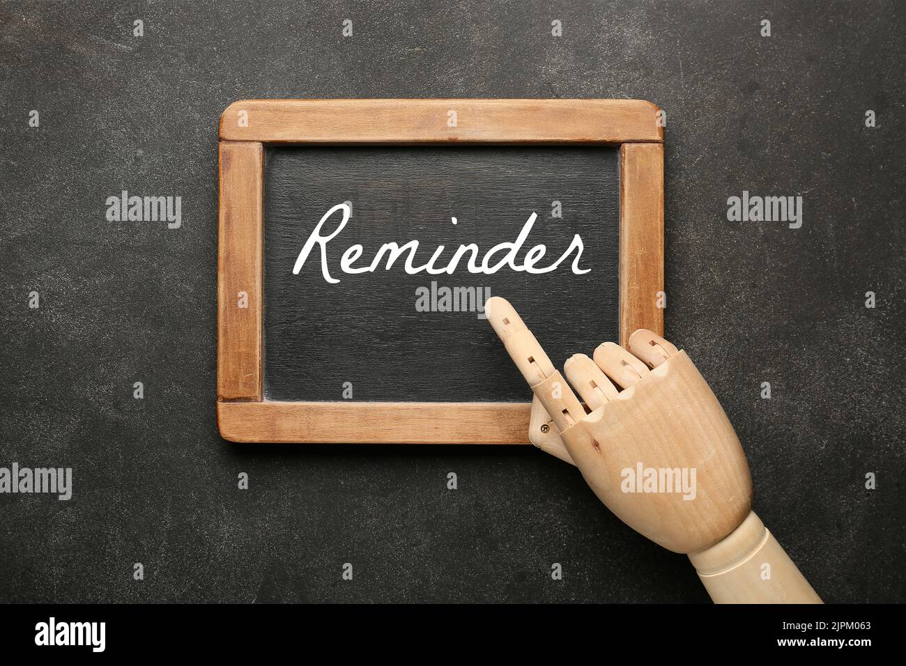 Wooden mannequin hand and chalkboard with word REMINDER on dark ...