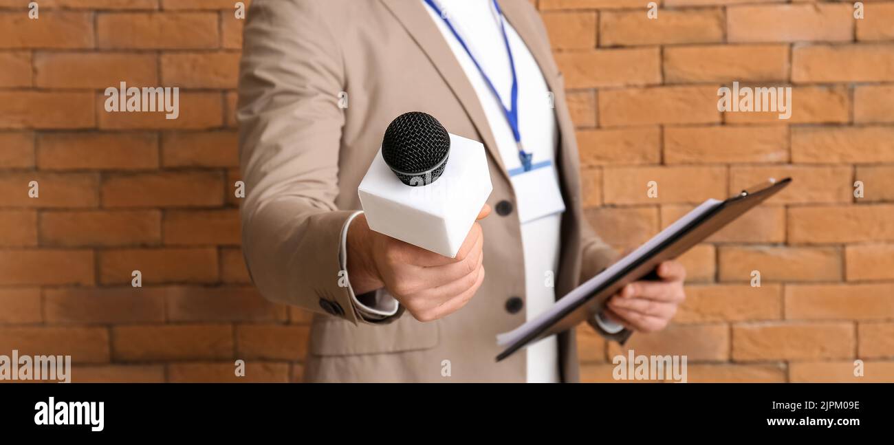 Male journalist with microphone on brick background, closeup Stock ...