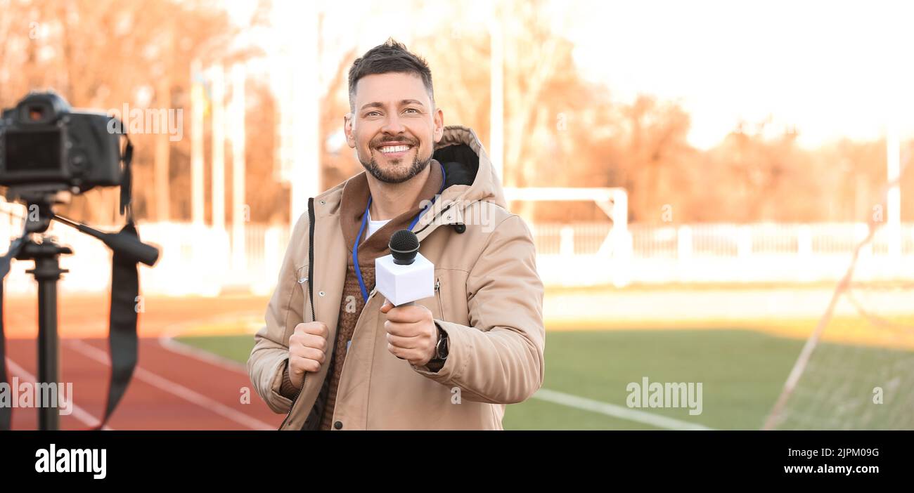 Male reporter with microphone at the stadium Stock Photo - Alamy