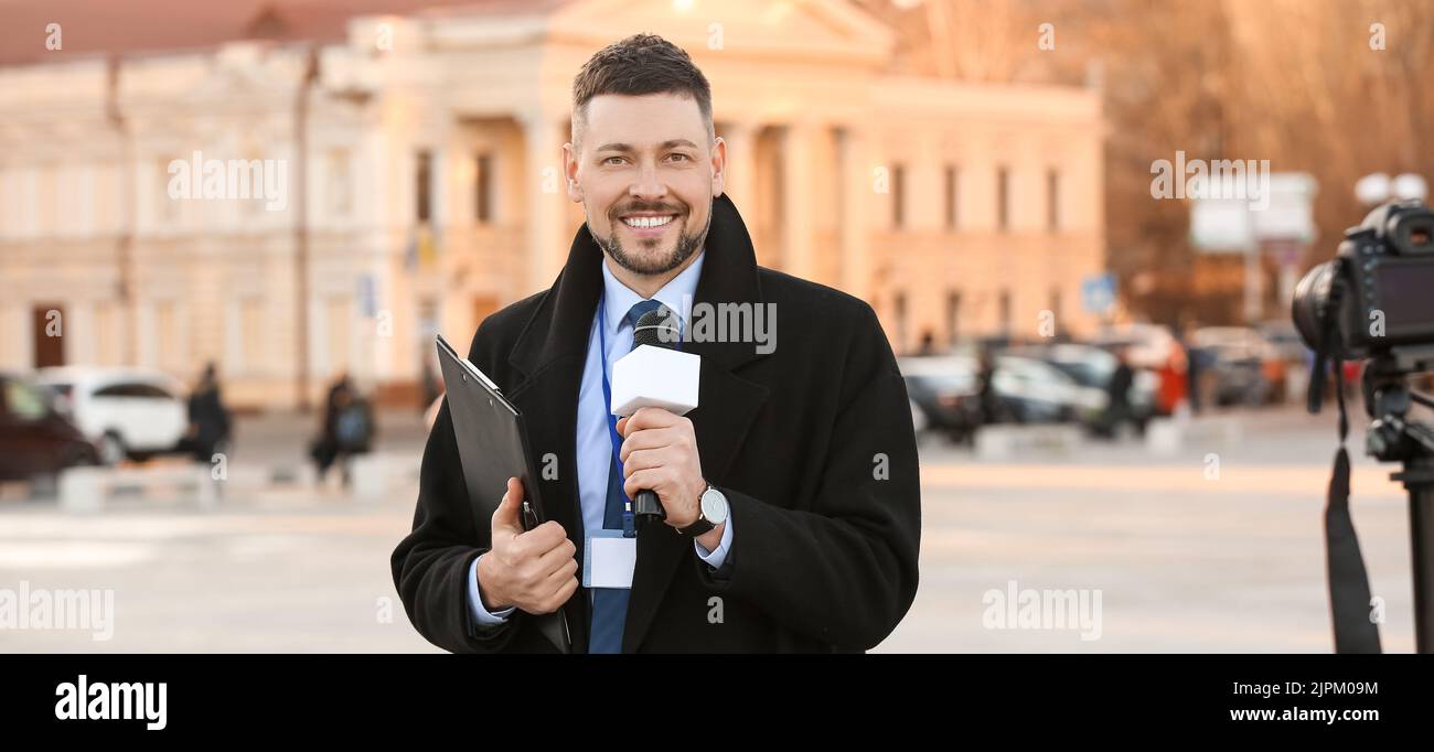 Male journalist with microphone outdoors Stock Photo - Alamy