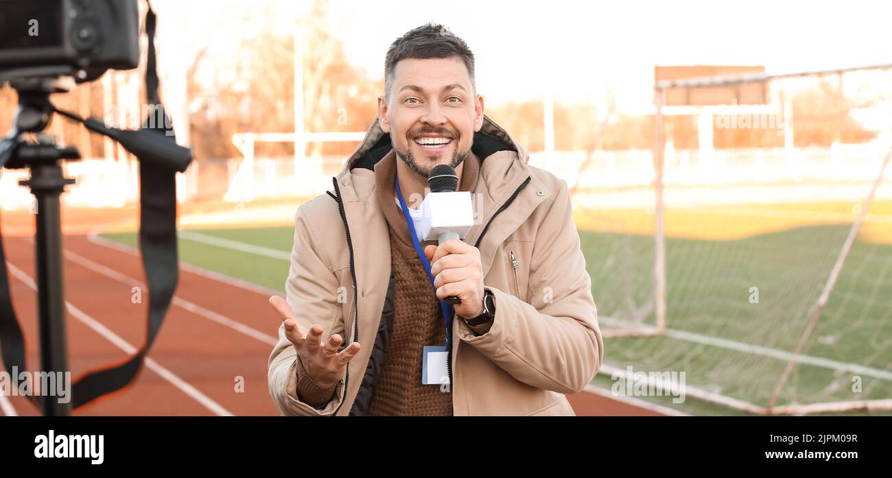 Male reporter with microphone at the stadium Stock Photo - Alamy