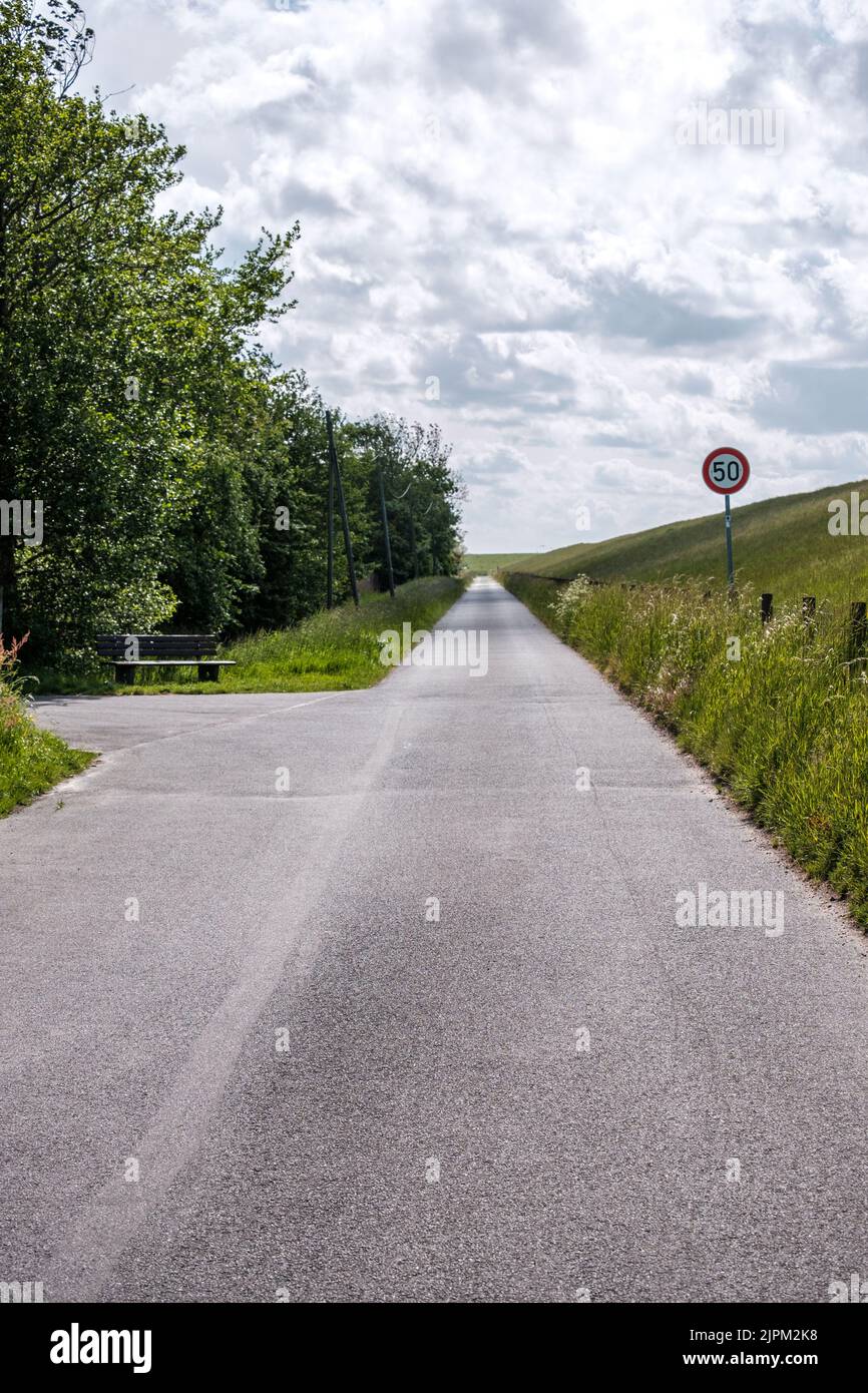 A vertical shot of an empty asphalt road with a sign of speed limit 50 ...