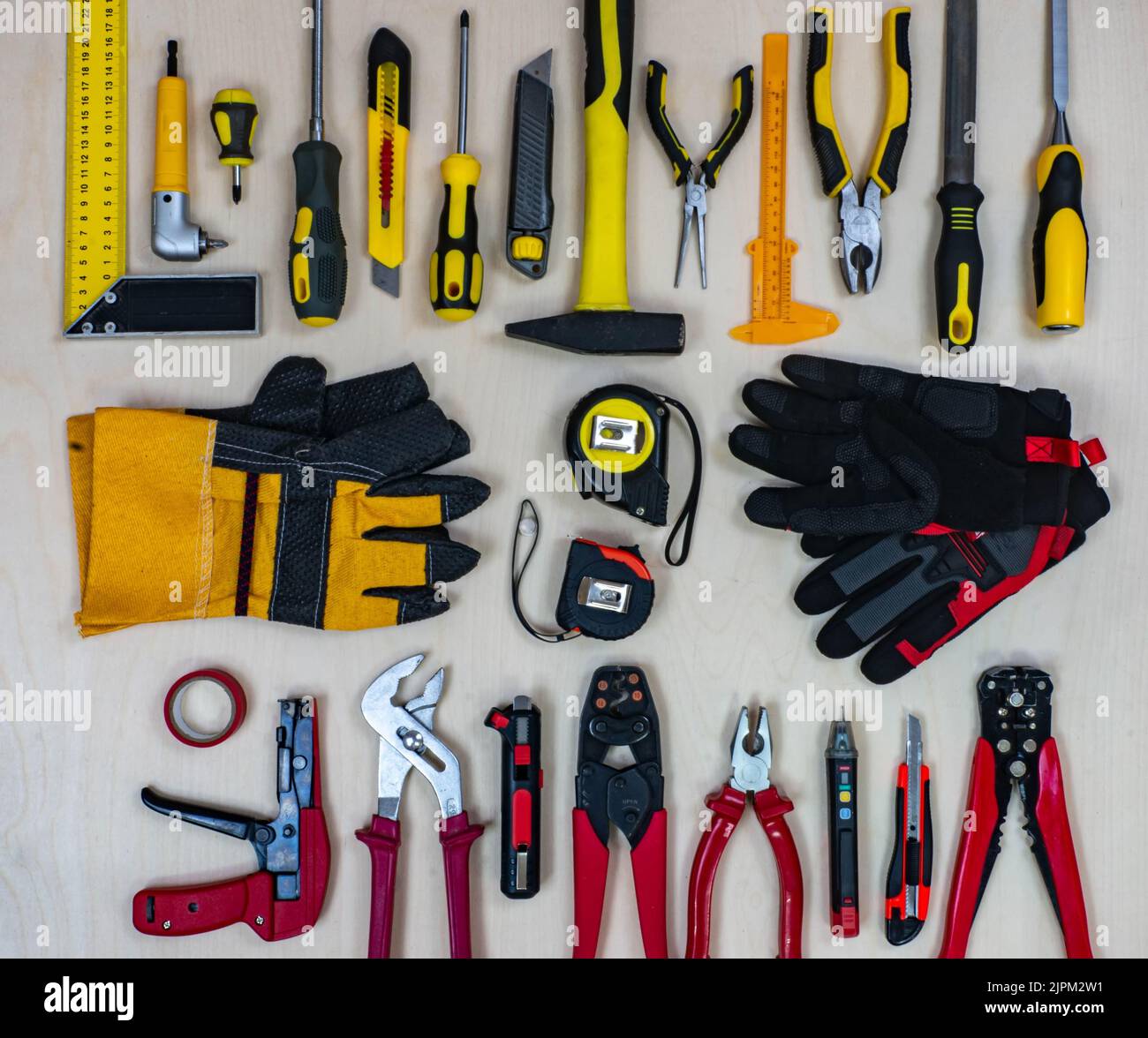 A red construction tools opposite a yellow working tools on a plywood ...